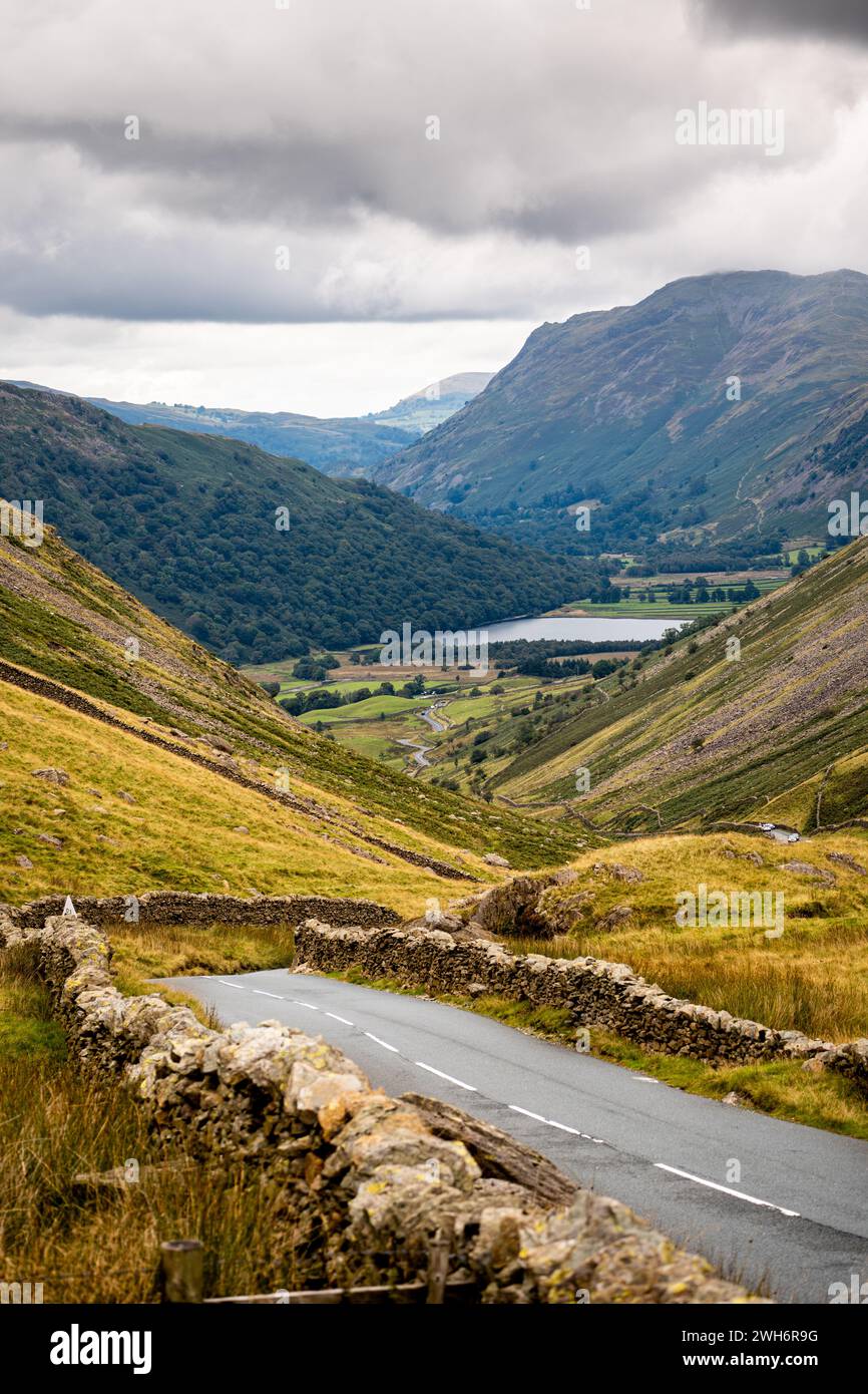 A scenic uphill mountain road with a serene lake in the background ...