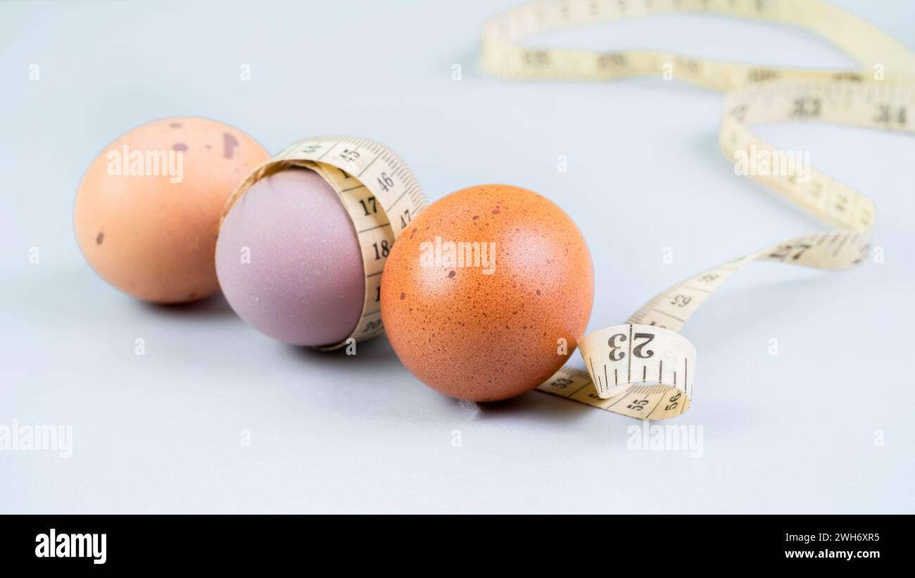Chicken egg wrapped in measuring tape on egg on white background ...