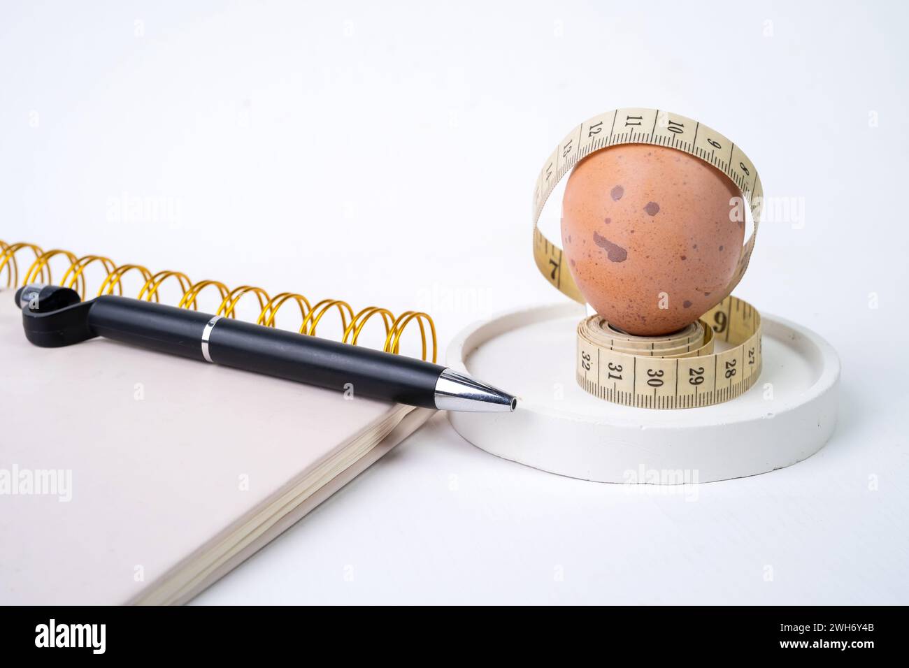 Chicken egg and measuring tape and pen on white background. Dieting ...