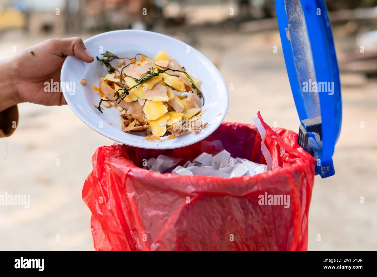 A man's hand pouring leftover food from a plate into the trash Stock ...