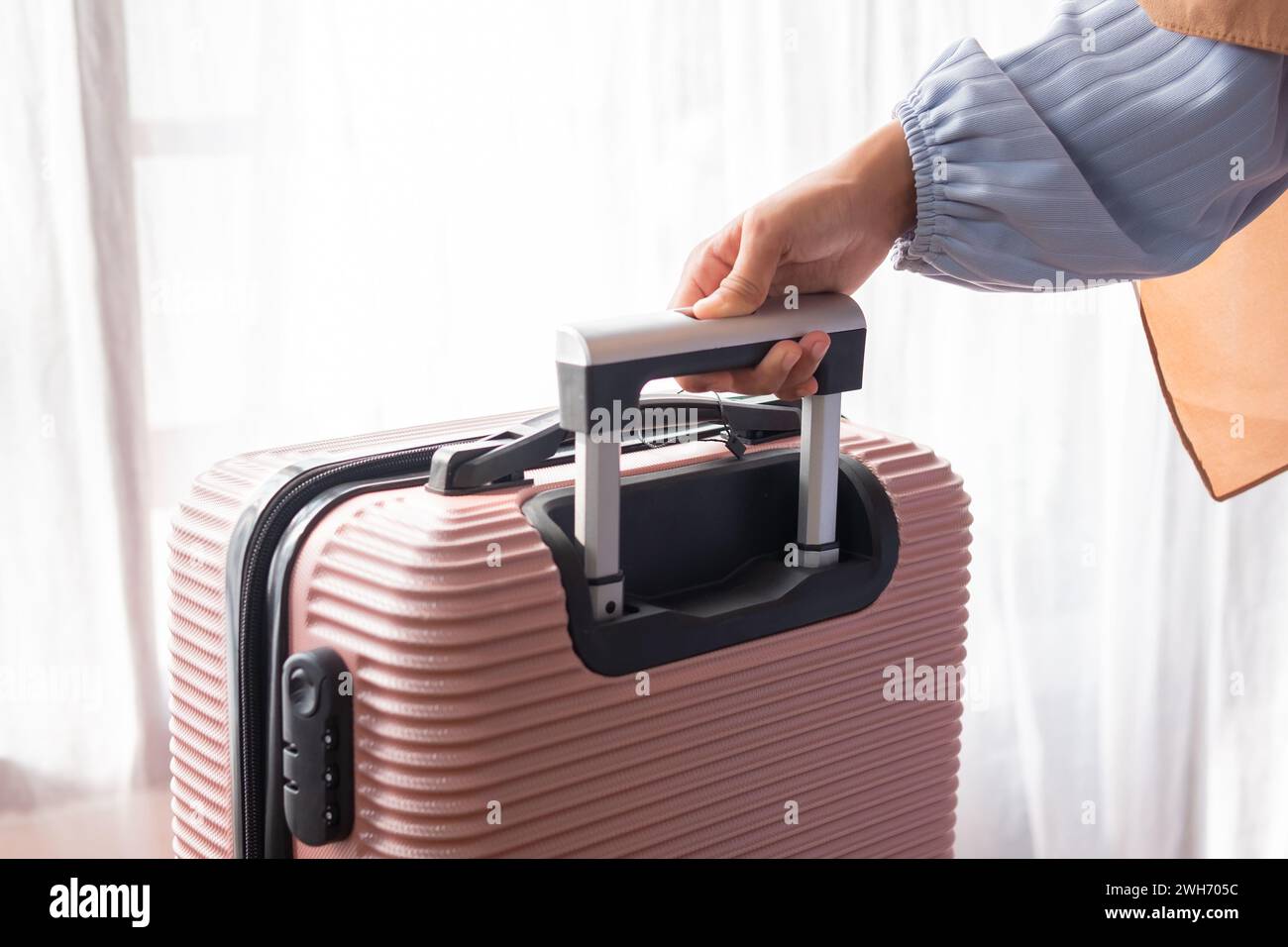 An Asian woman's hand pulls the handle of a suitcase isolated on a ...