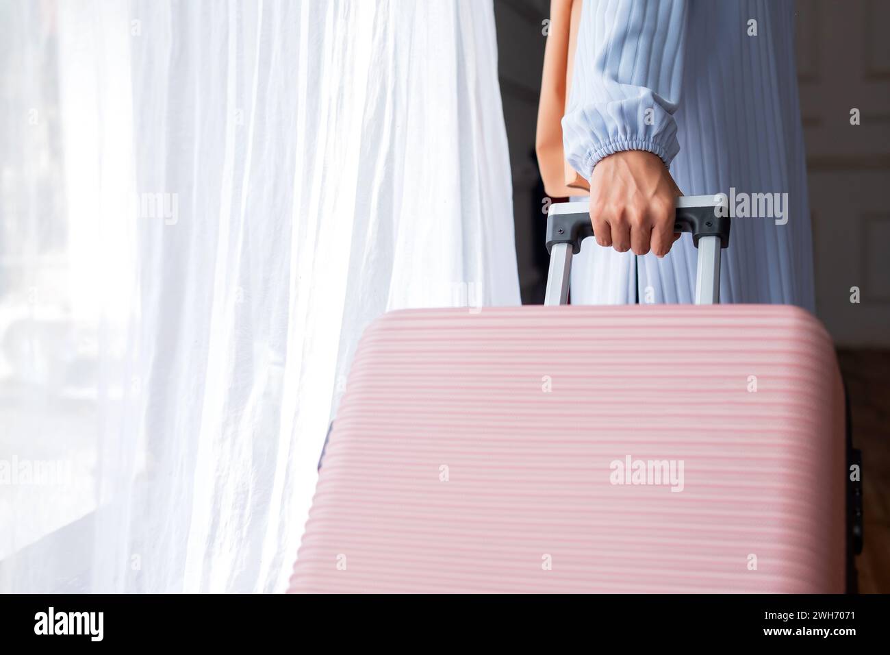An Asian woman's hand pulls the handle of a suitcase isolated on a ...