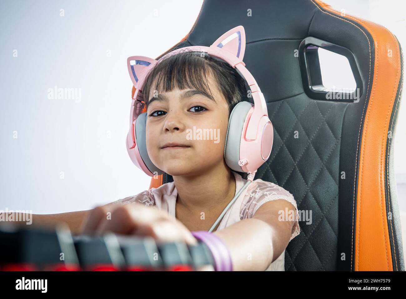 Portrait of a little girl with PC gamer accessories. She looks at the ...
