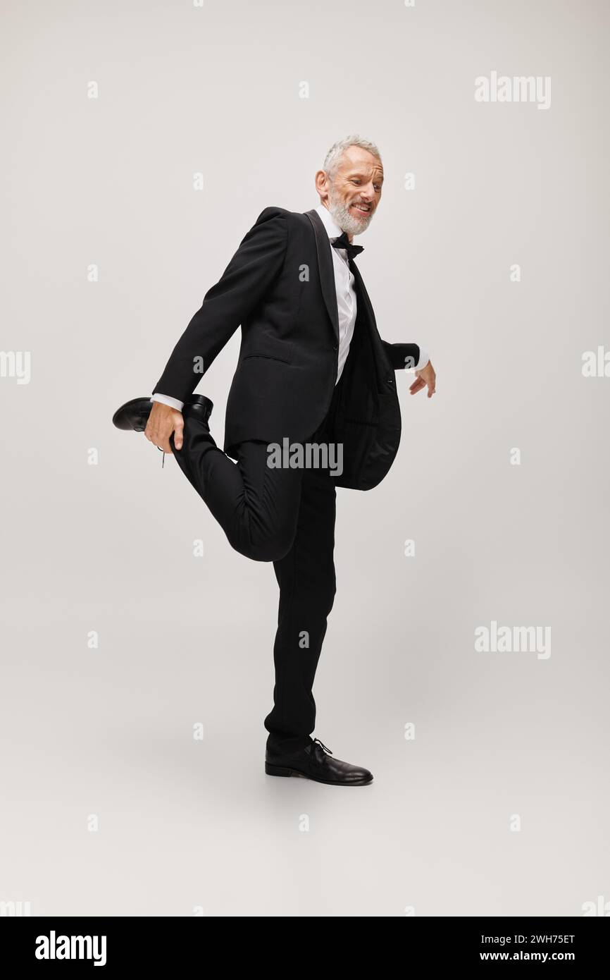 joyous good looking mature man in elegant suit with bow tie dancing ...
