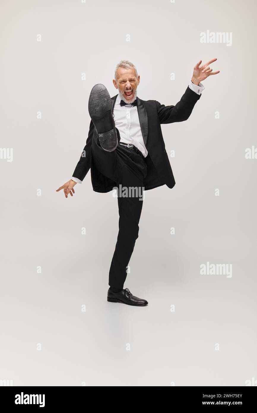 joyful good looking mature man in elegant suit with bow tie dancing ...