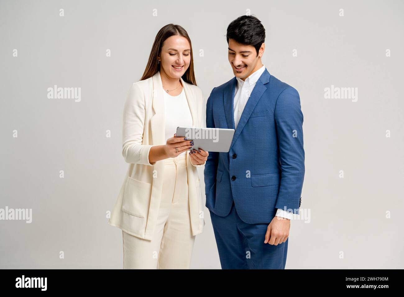 A professional woman and man team, in a beige suit and blue suit ...