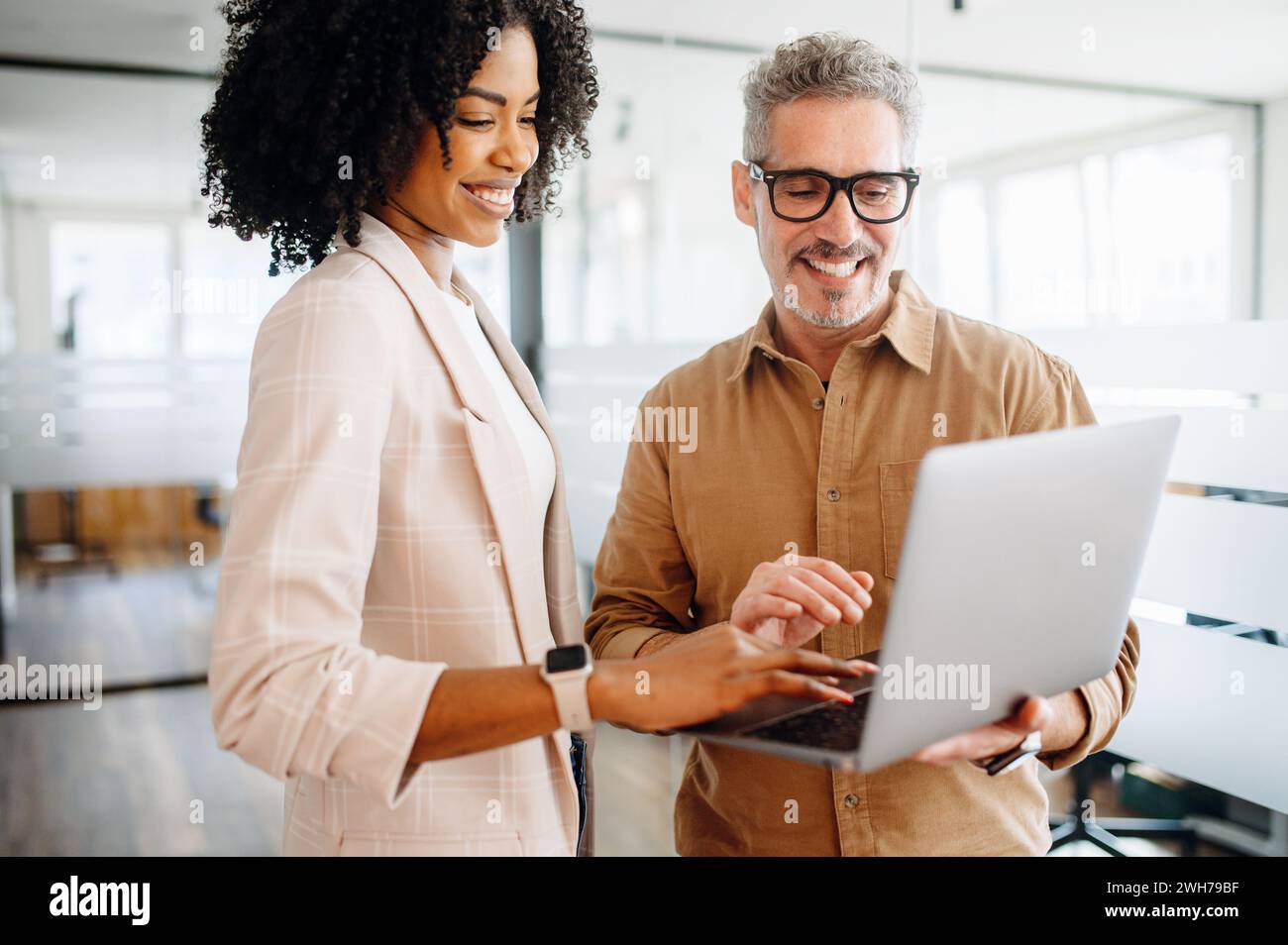 A cheerful businesswoman leads a laptop discussion with a beaming ...