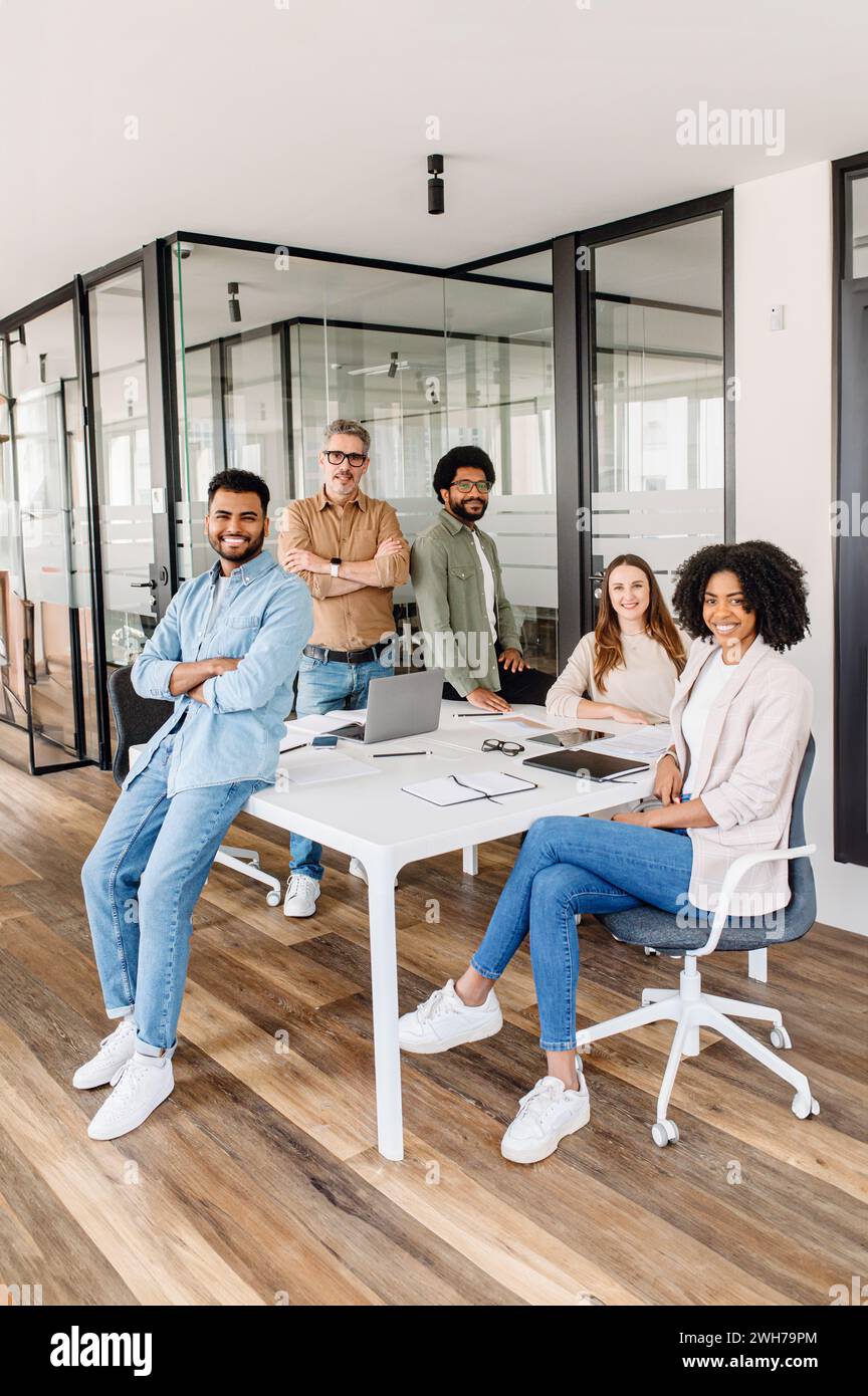 A vibrant team gathers around a minimalist white table in their bright ...