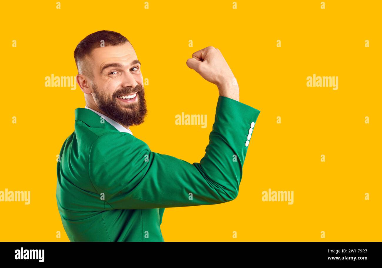 Happy man in green suit smiles, flexes his arm and shows his strong ...