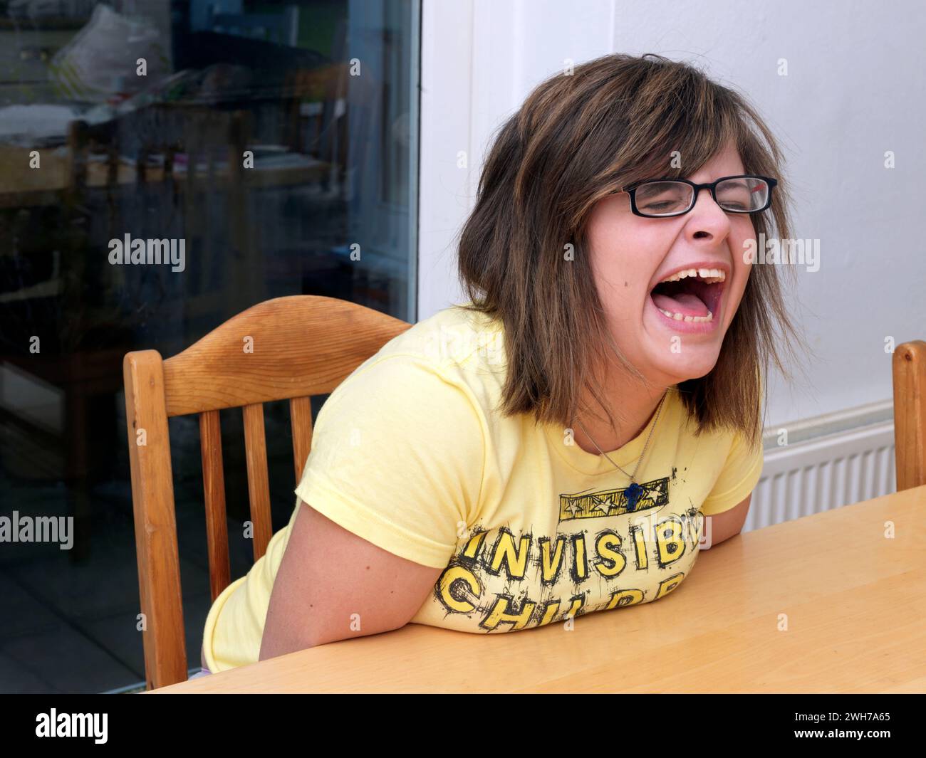 Portrait of Teenager sitting down at Table in Conversation Laughing ...