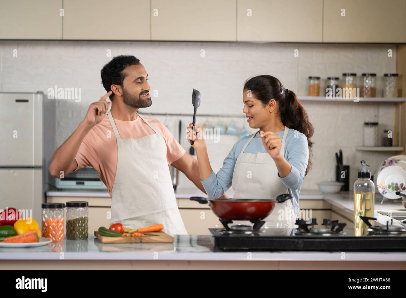 Joyful Indian couples at kitchen dancing together while cooking ...
