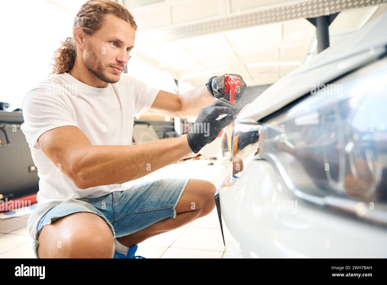 Long-haired guy works with special clay in car detailing Stock Photo ...