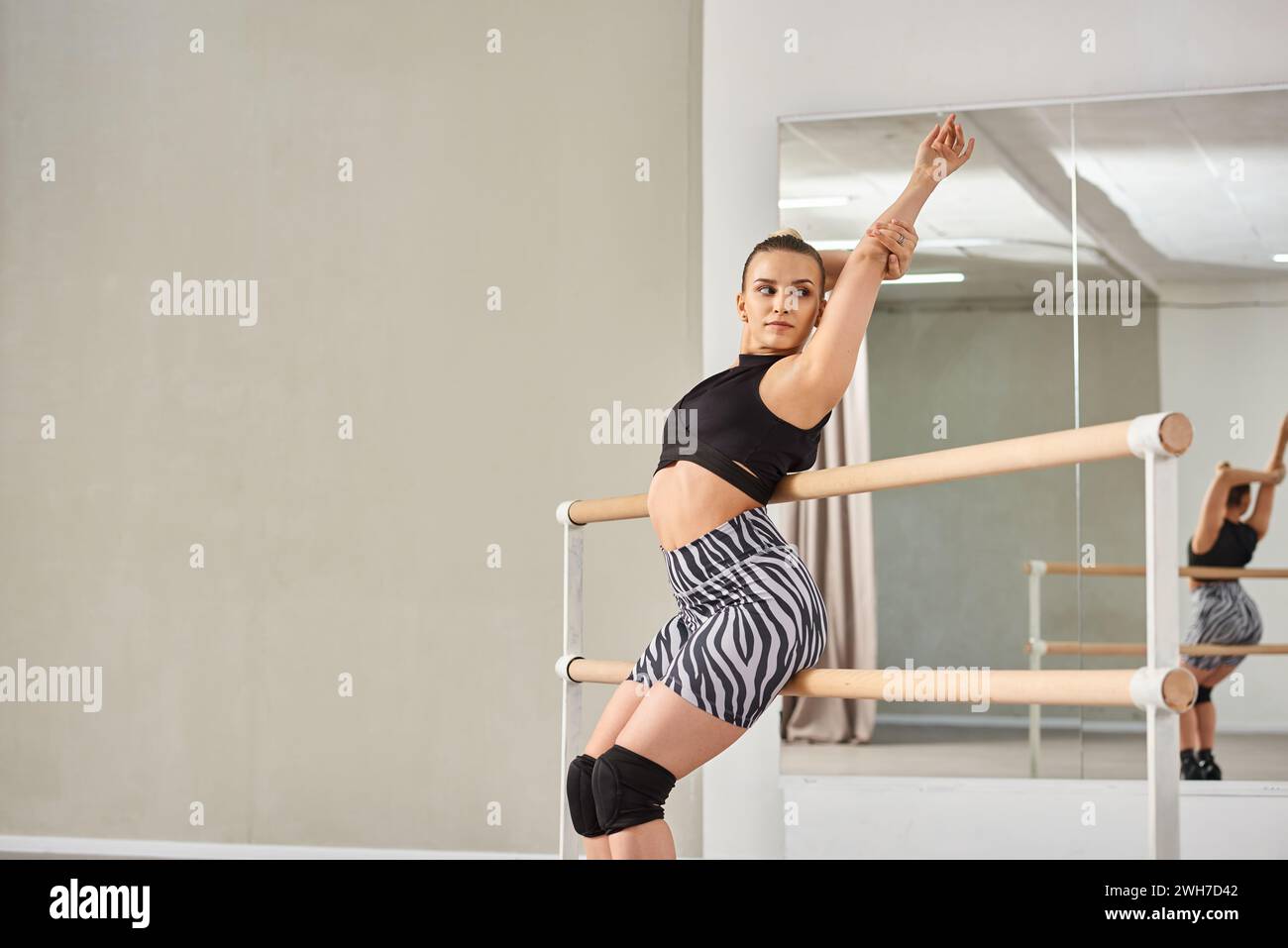 A graceful woman stretching her body on a ballet bar, showcasing ...
