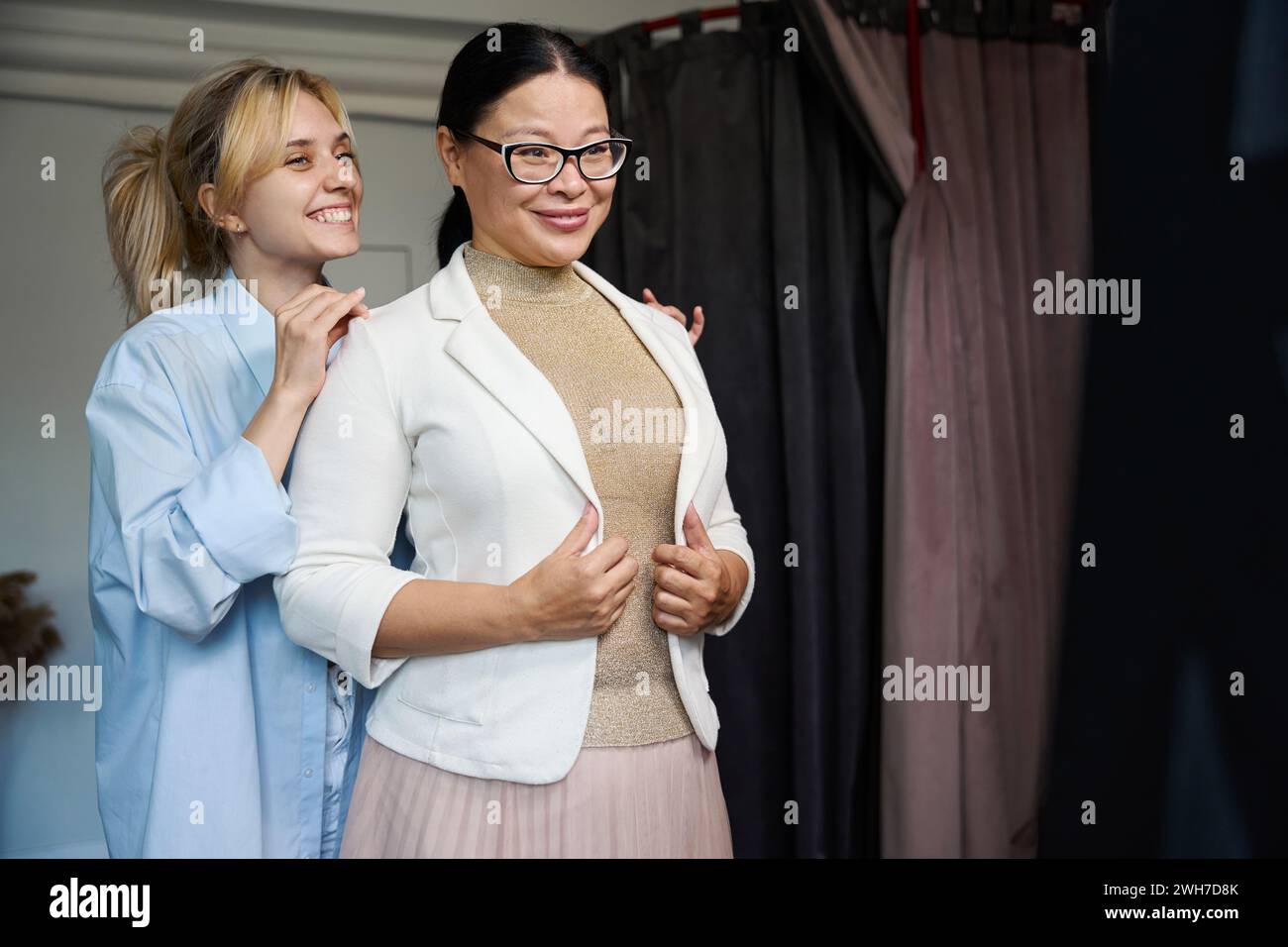 Blonde craftswoman helps a client try on a light jacket Stock Photo - Alamy