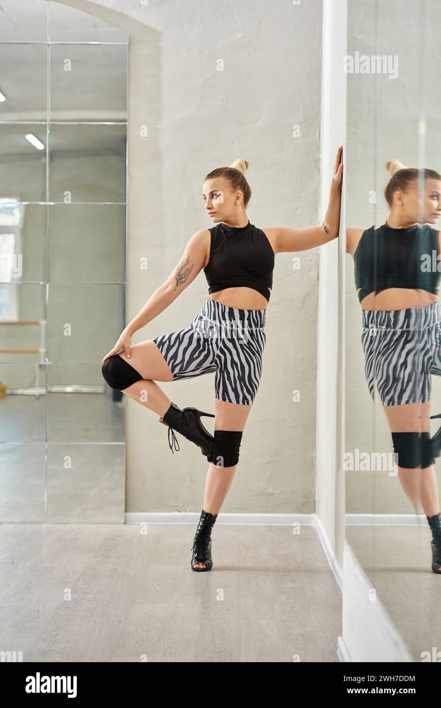 fashion-forward woman in zebra shorts and black top balances on one leg ...