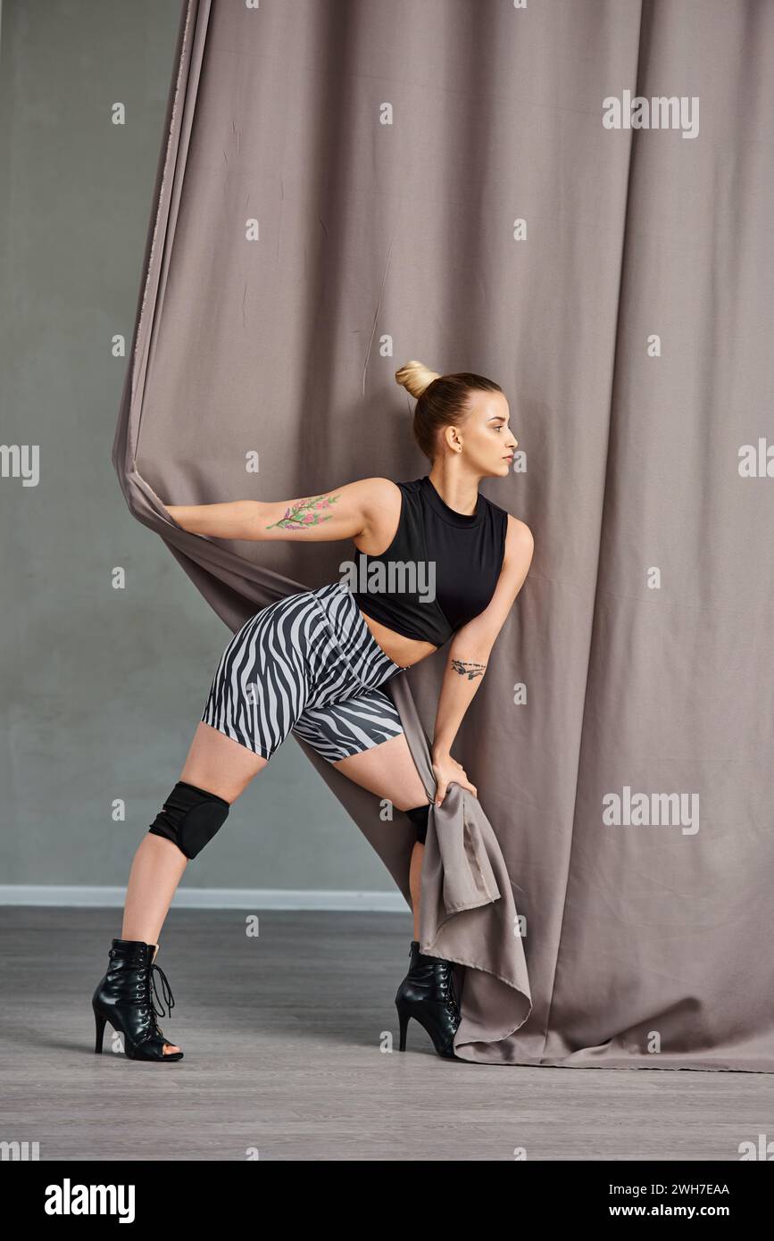 pretty woman in dance clothing and high heels gracefully poses against ...