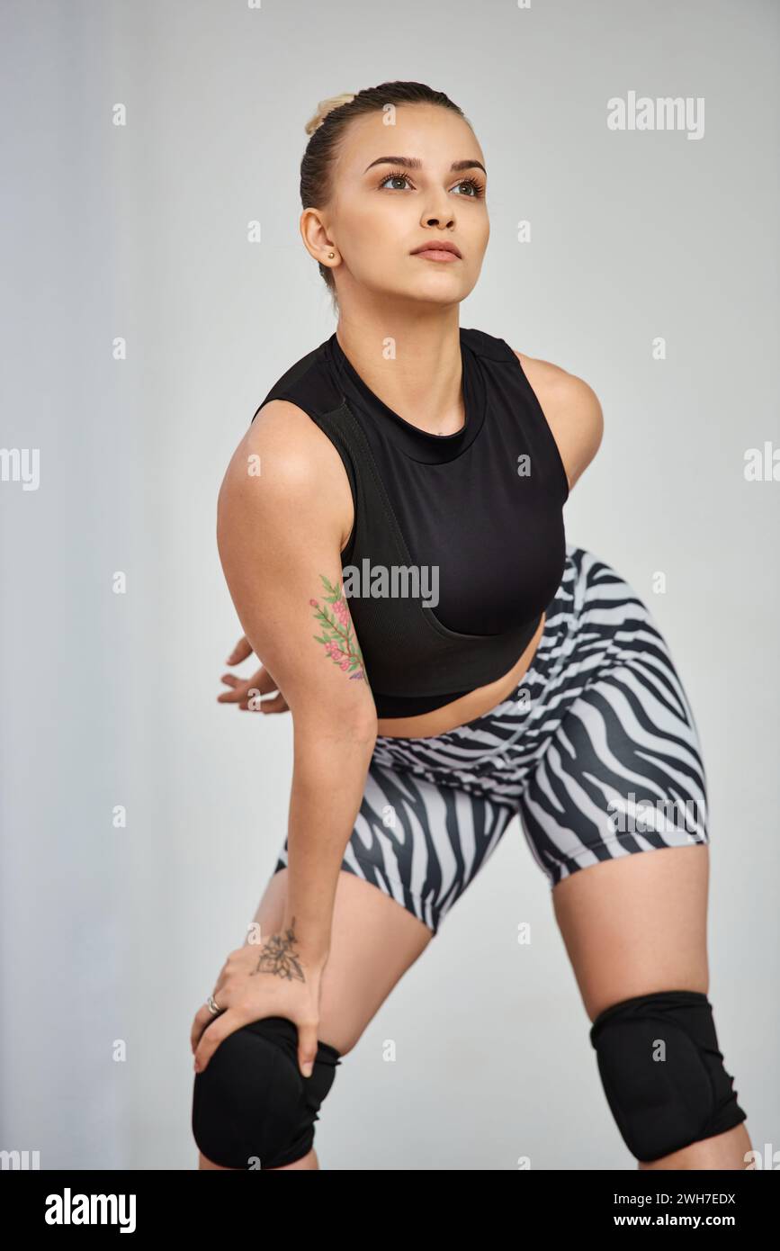 A confident woman in black tank top and zebra shorts balances on one ...