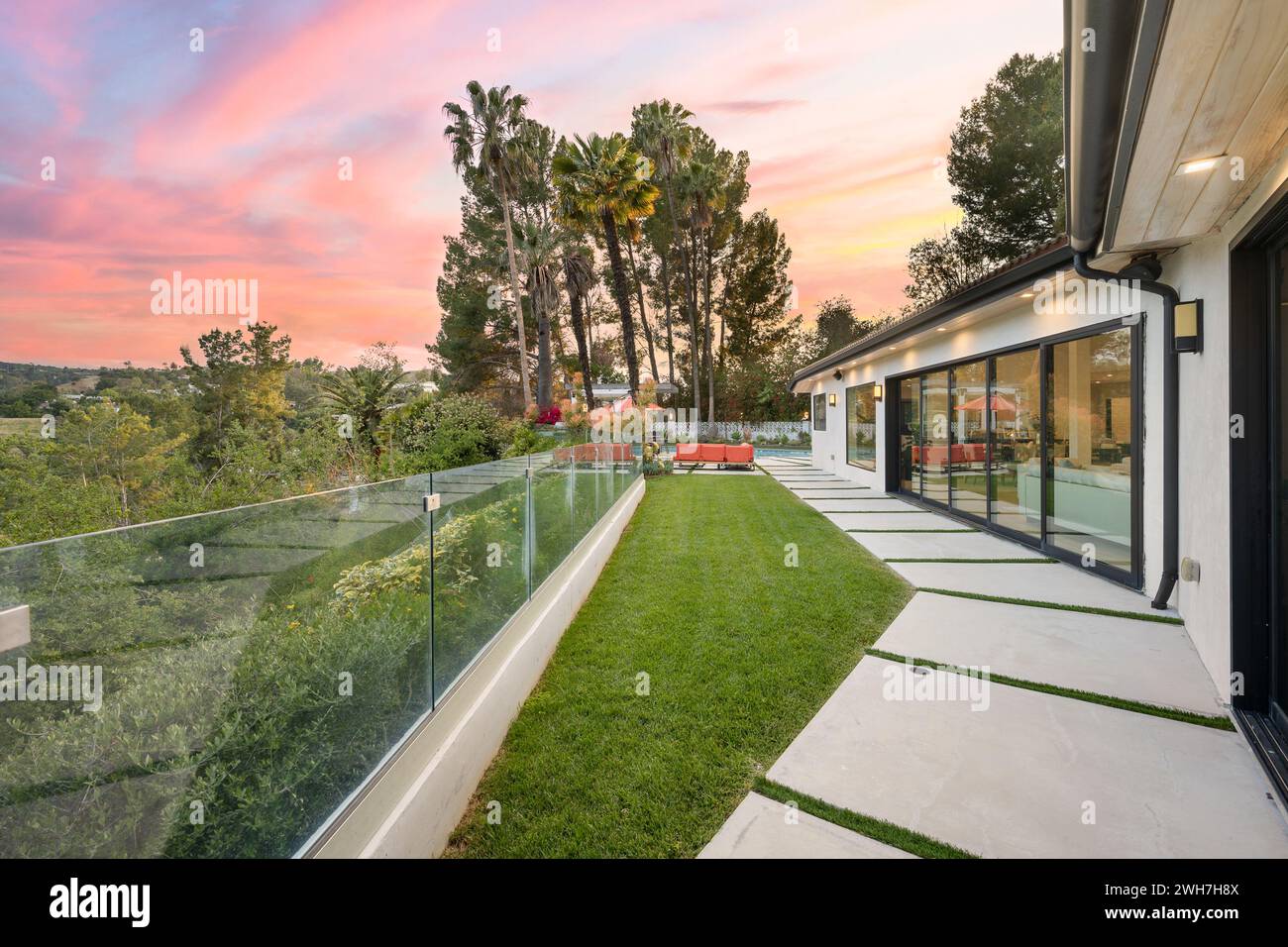 A backyard with glass railing and pathway, overlooking cityscape at ...