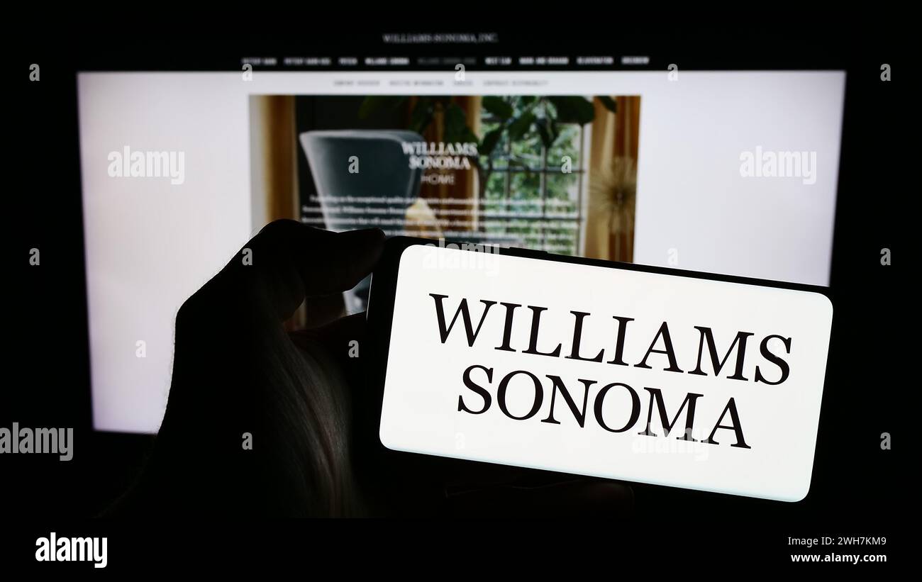 Person holding mobile phone with logo of American consumer retail company Williams-Sonoma Inc ...