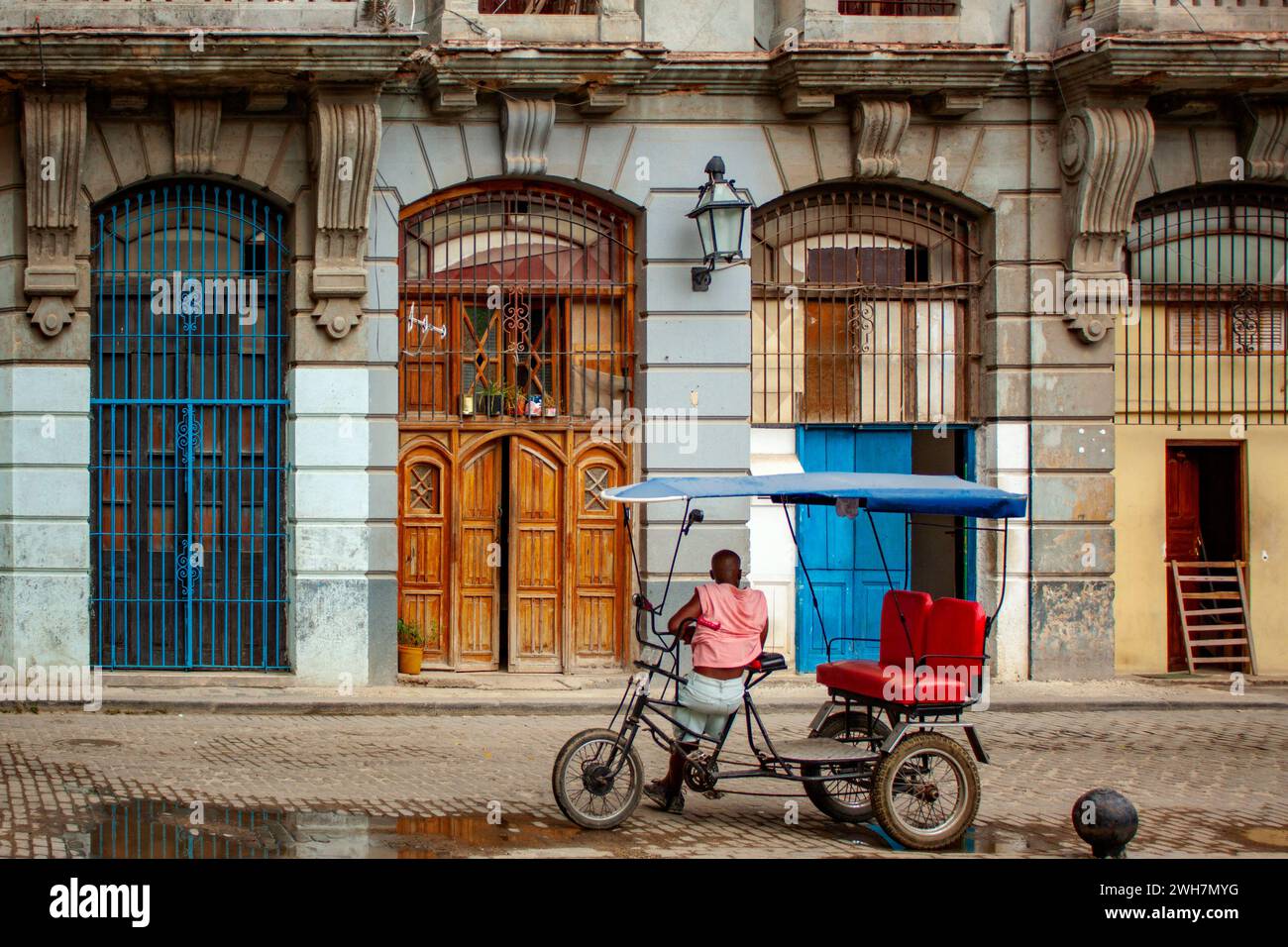 Tricycle taxi driver, waiting for passenger, on a classic Old Havana ...