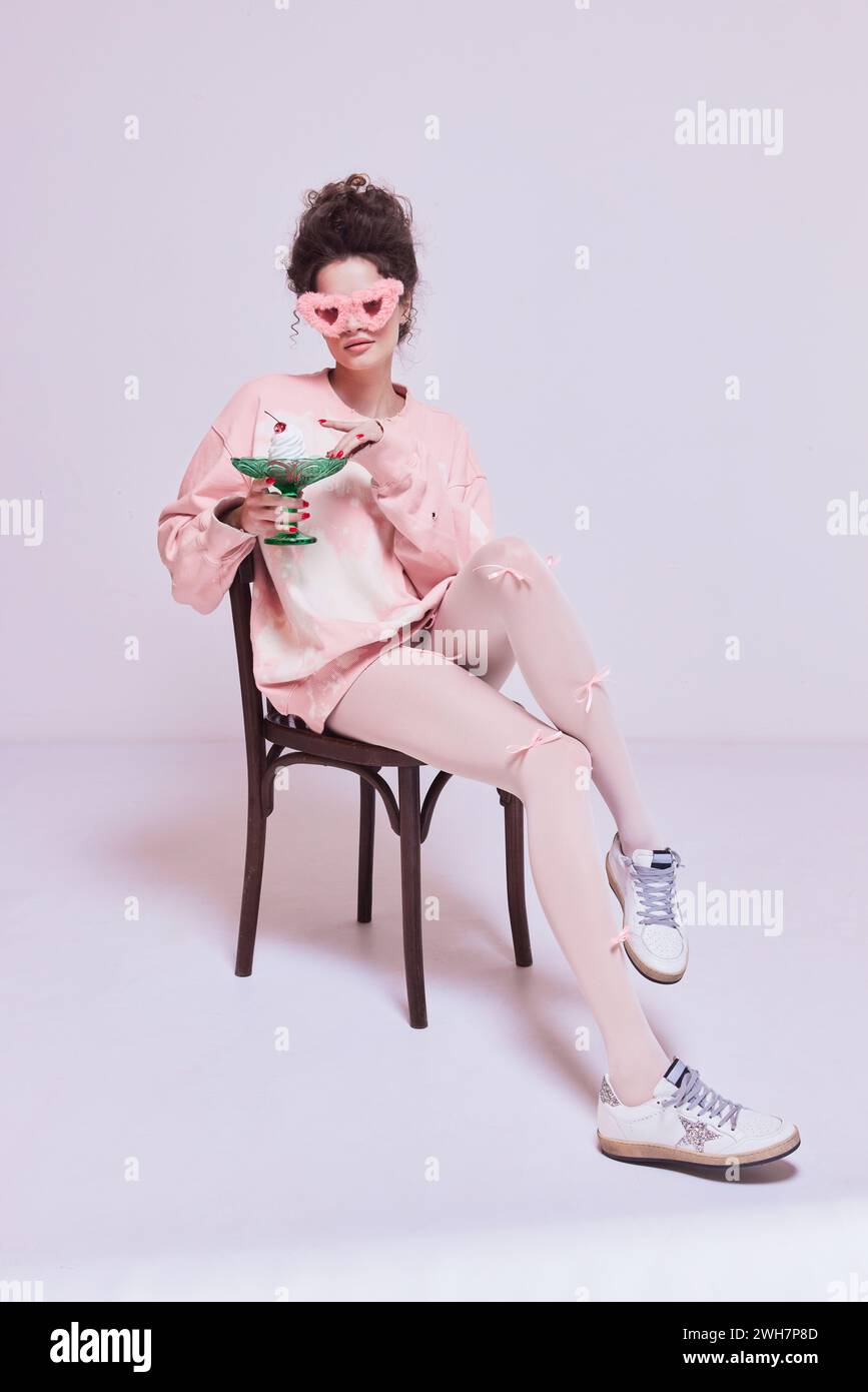 Young pretty woman sitting on chair in pink comfortable clothes and ...