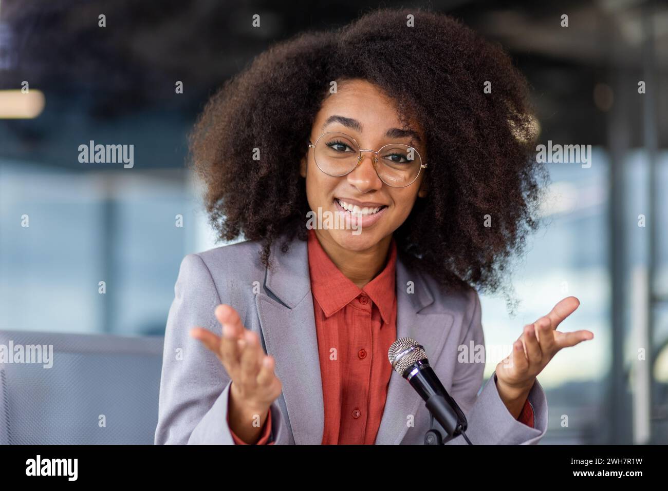 A happy woman, wearing a blazer, with a Jheri curl, smiles, and ...