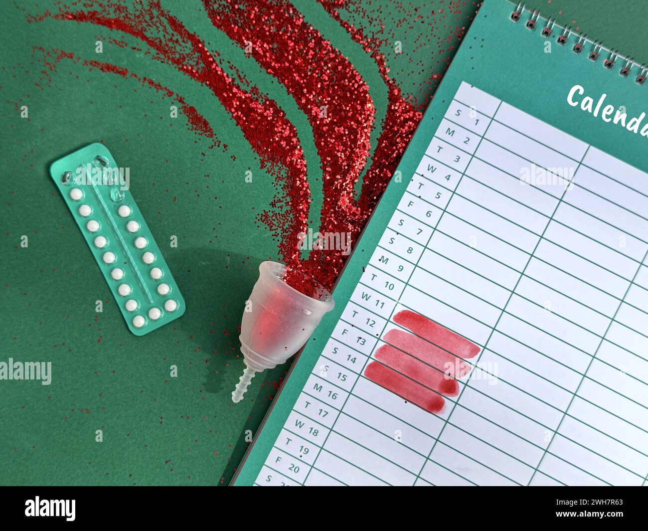 A menstrual cup with red glitter, alarm clock, contraceptive pills, and ...