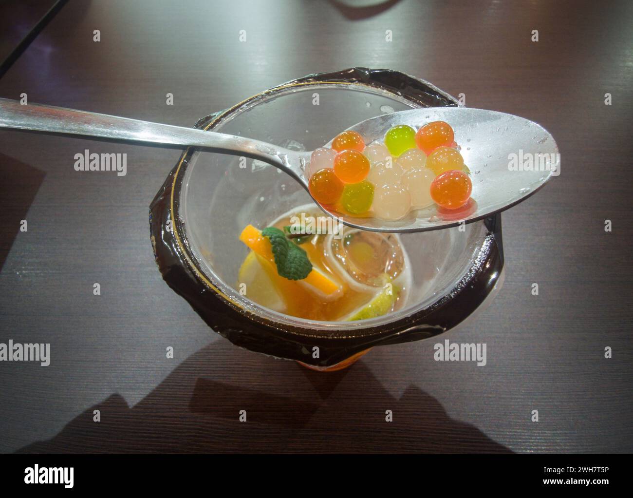 Spoon full of chewy spheres pover takeaway cup of bubble tea. Wooden ...