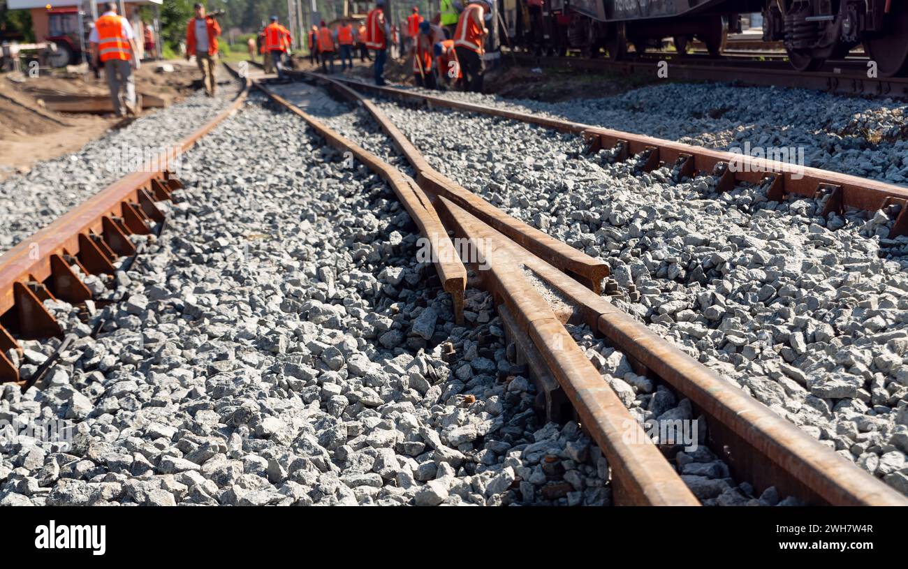 Railway repair. Uniformed workers are changing the old railway line ...