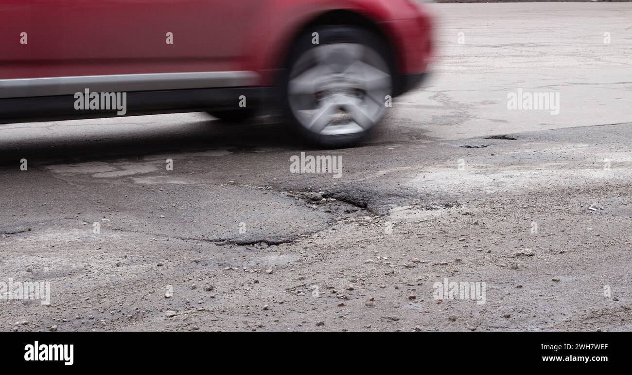 The car goes around a pothole on the road. Broken asphalt after winter ...