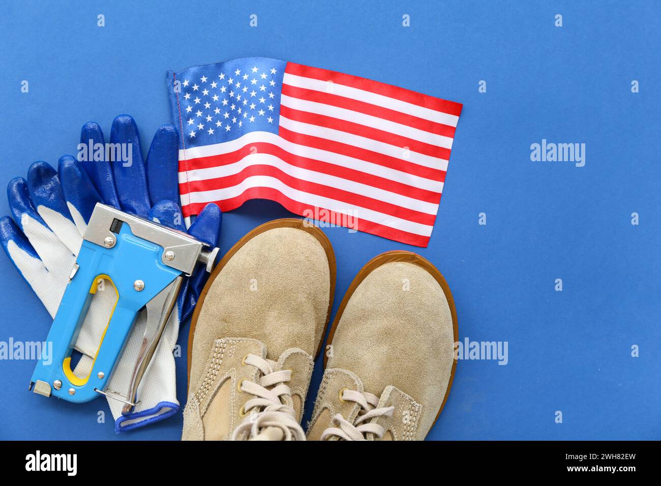 Industrial stapler, boots, gloves and USA flag on blue background ...