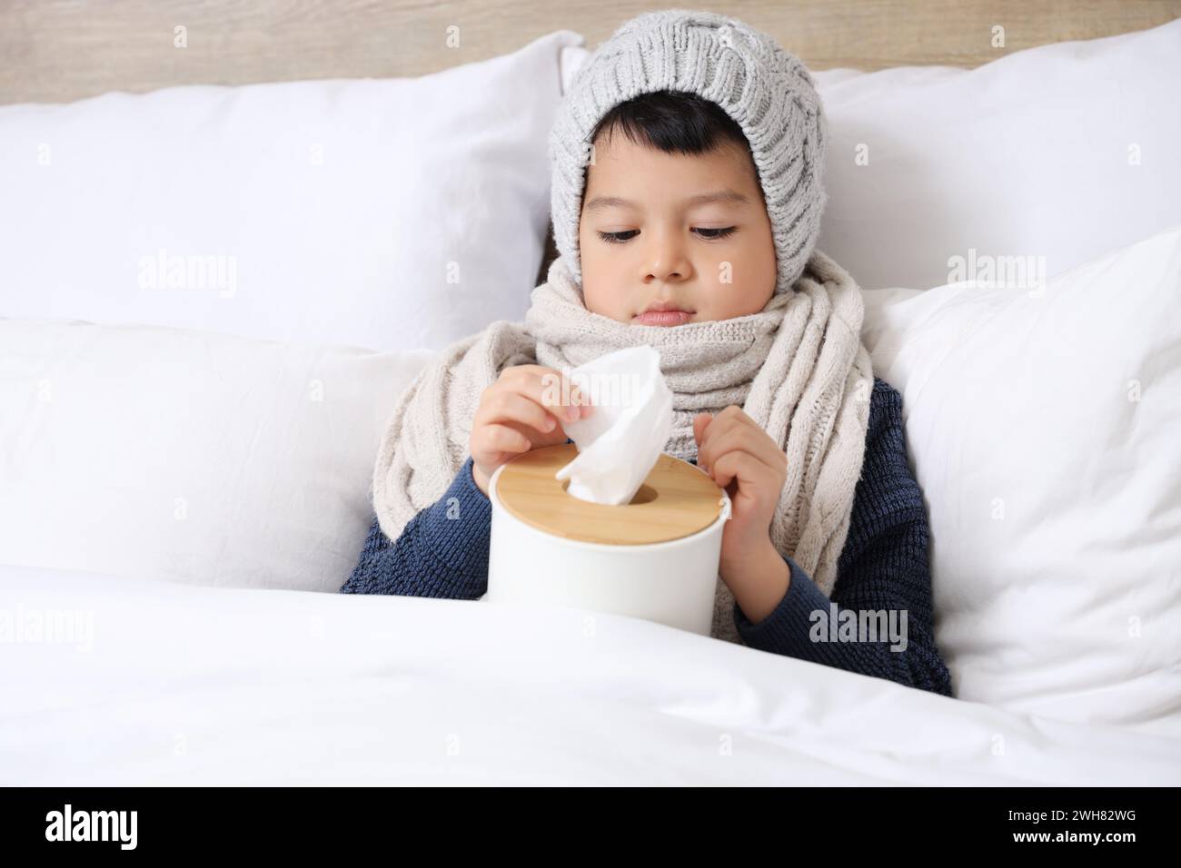 Ill little Asian boy taking tissue from box in bedroom Stock Photo - Alamy
