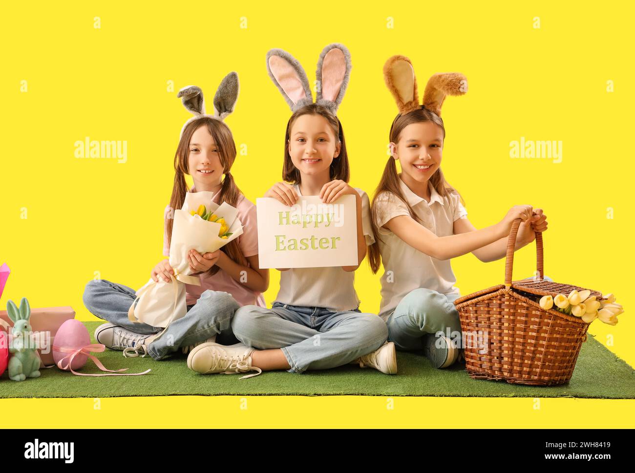 Cute little girls celebrating Easter on yellow background Stock Photo ...