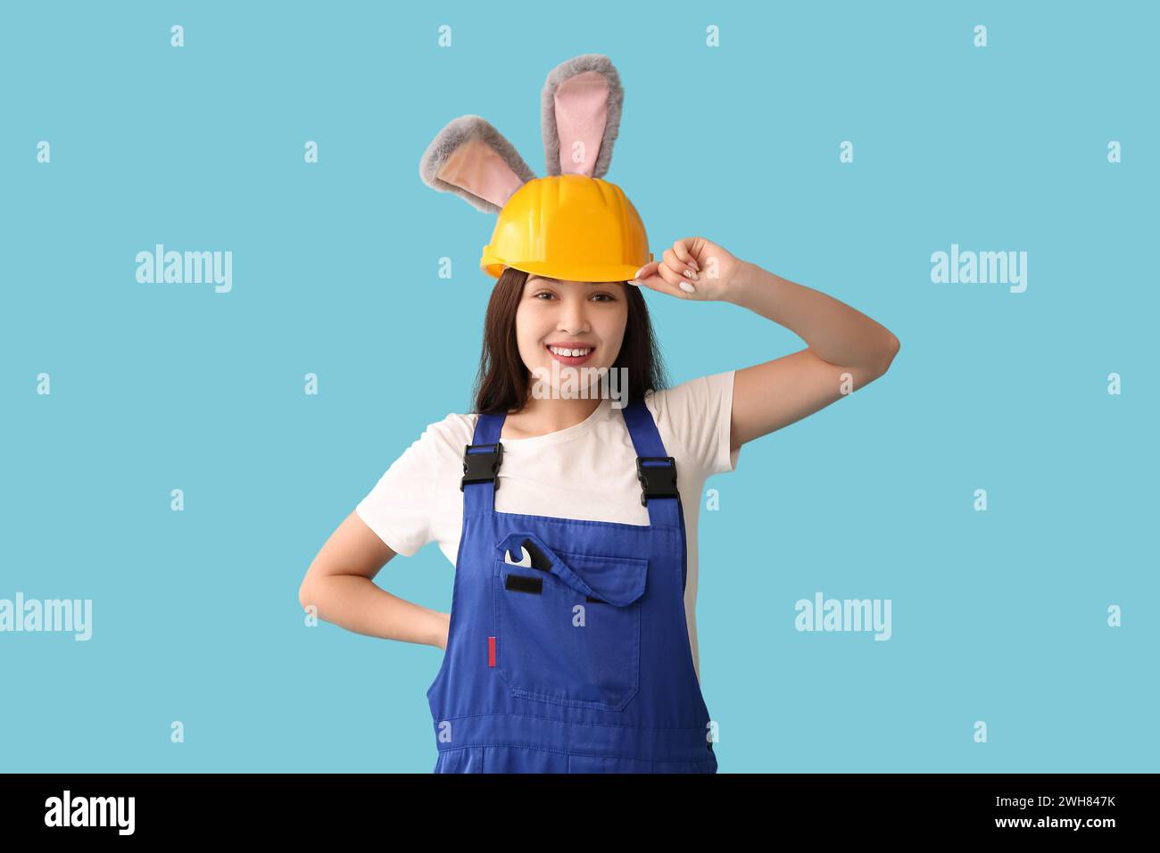 Female Asian worker in bunny ears on blue background. Easter ...