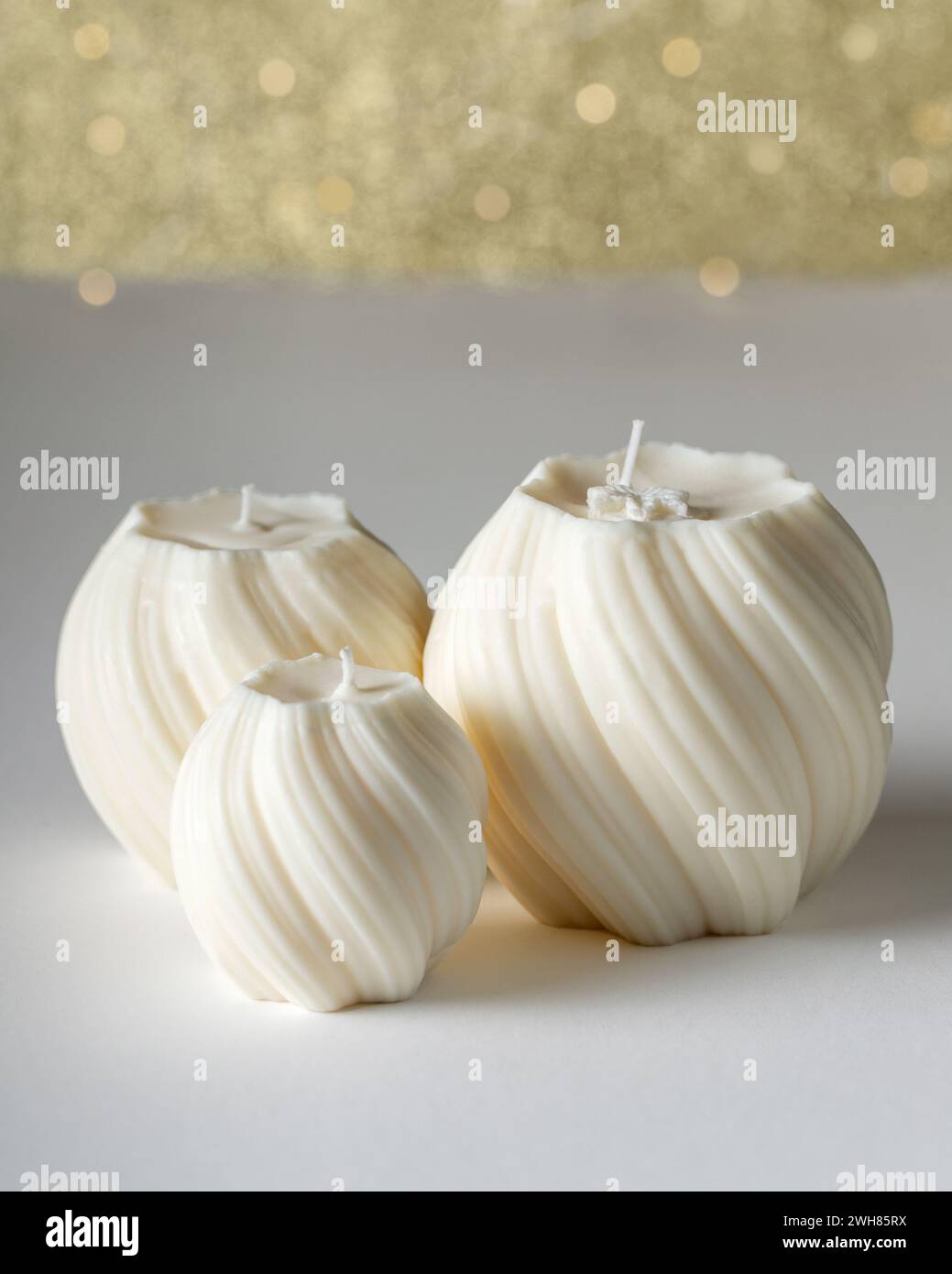Three soy wax handmade candles of different sizes on white table with ...