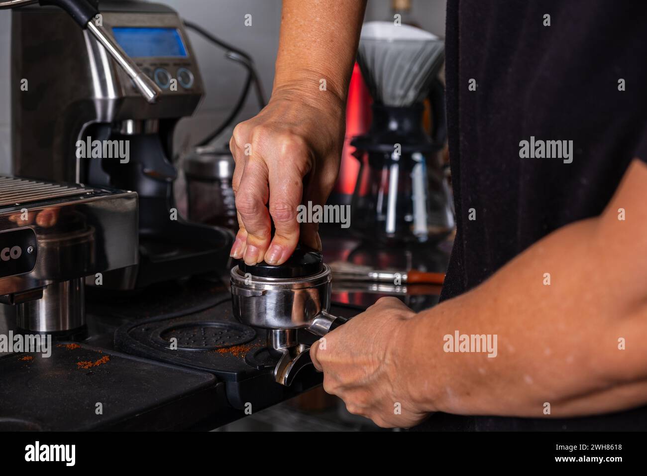 woman's hands pressing roasted and ground coffee to use in coffee maker ...