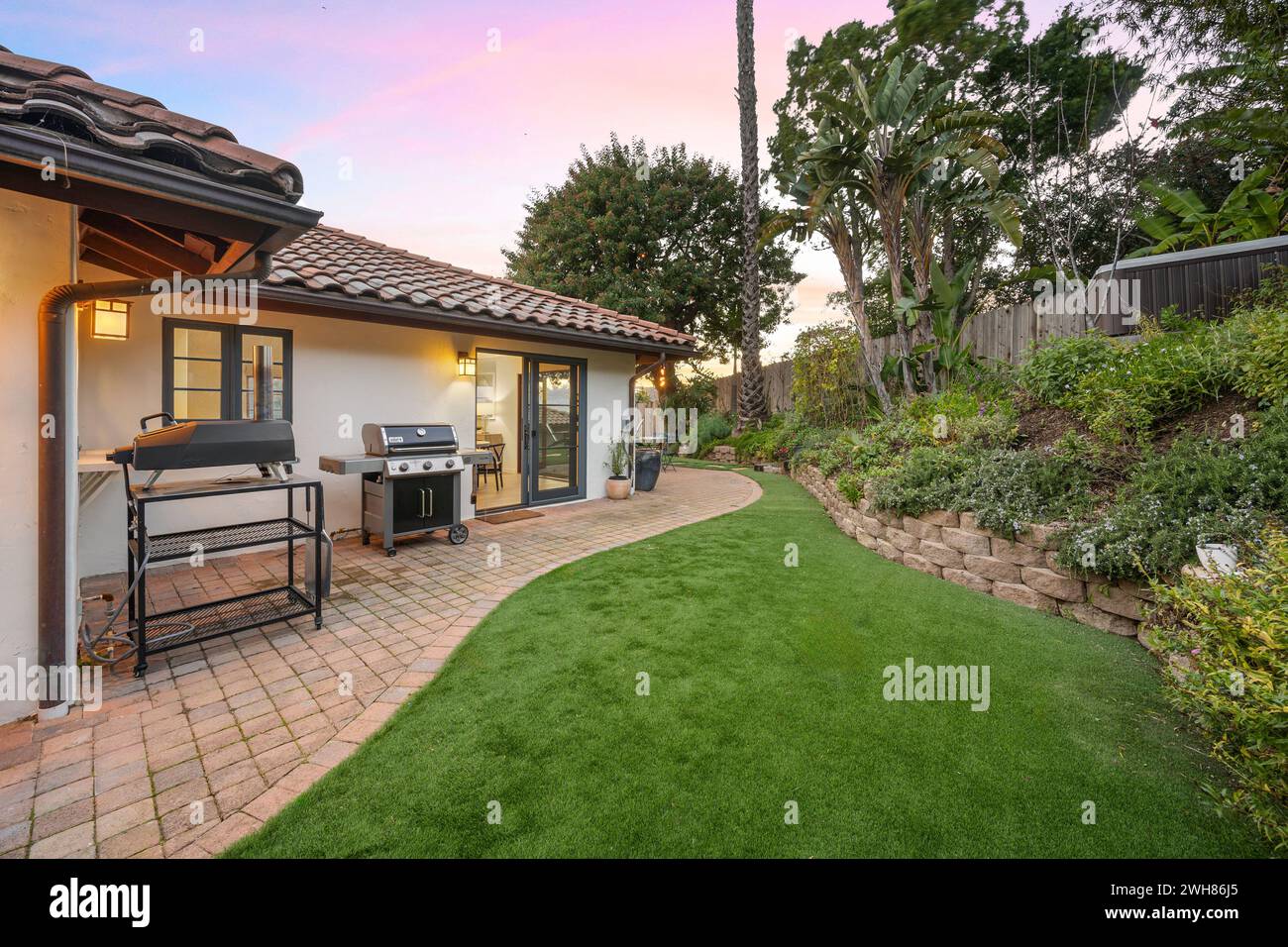 A well-maintained backyard featuring a lush grass lawn and a grill ...