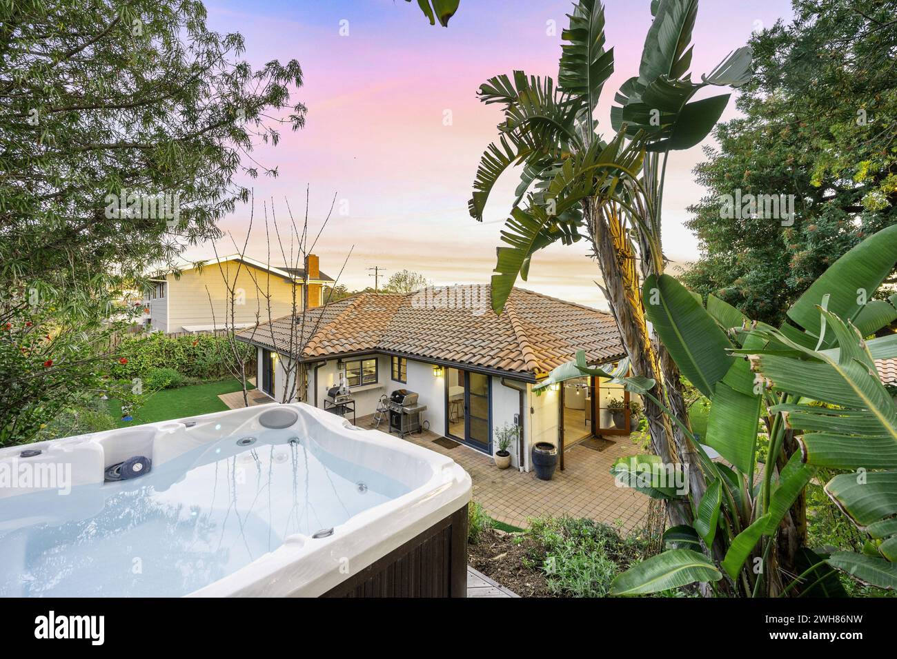 A backyard oasis featuring a luxurious hot tub nestled beside a charming structure Stock Photo ...