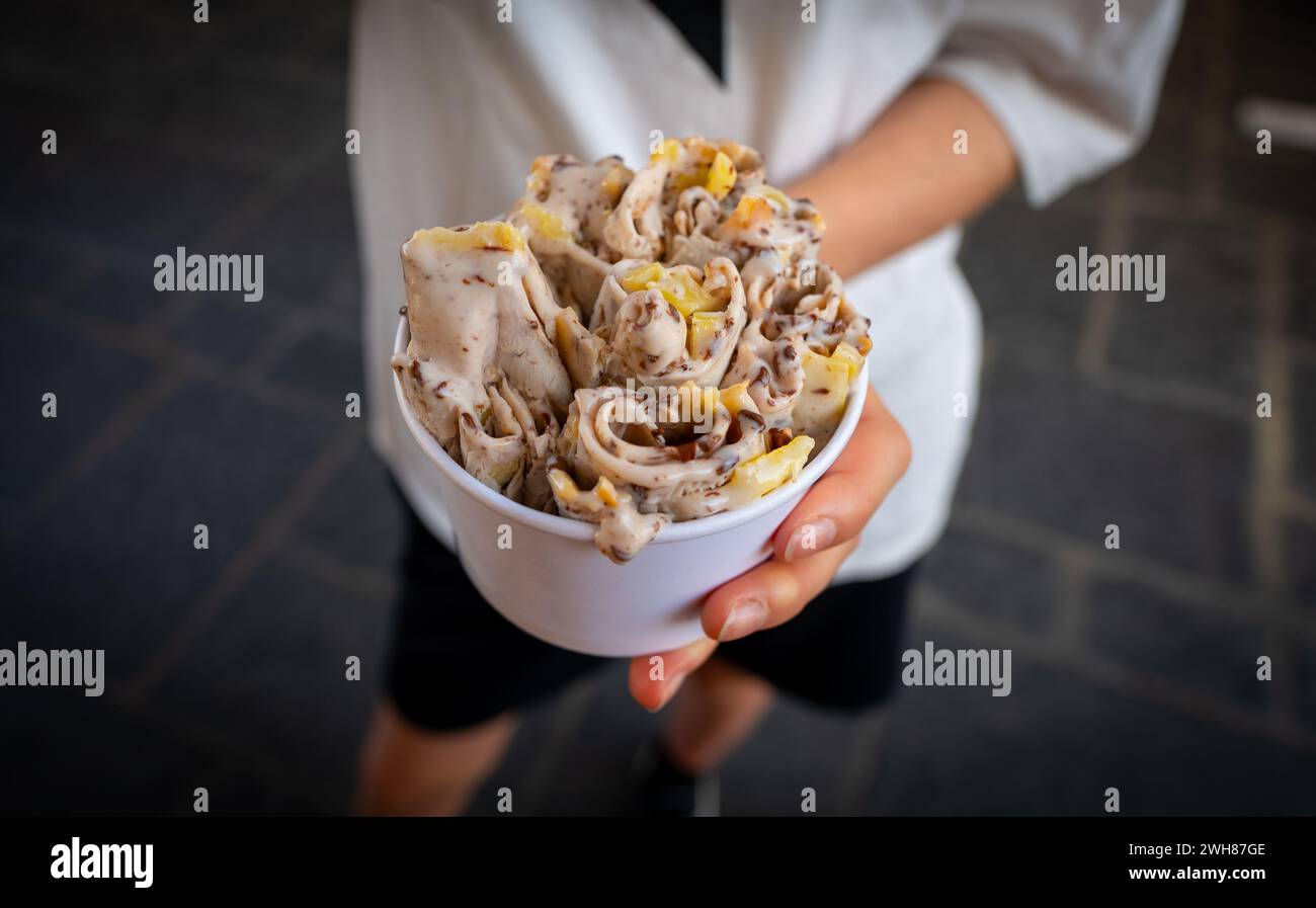 Rolled ice cream in cup in girl hands at street Stock Photo - Alamy