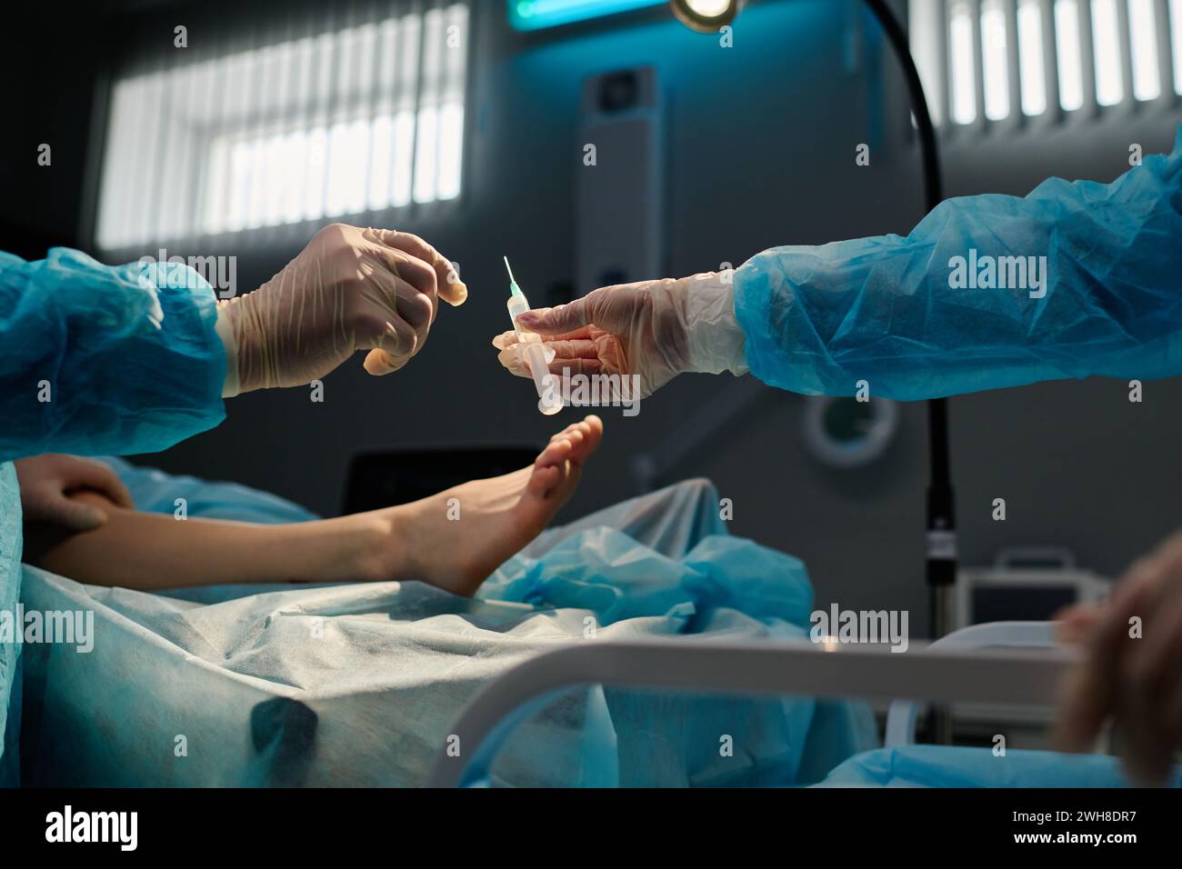 Gloved hand of surgeon taking syringe with local anaesthesia during ...