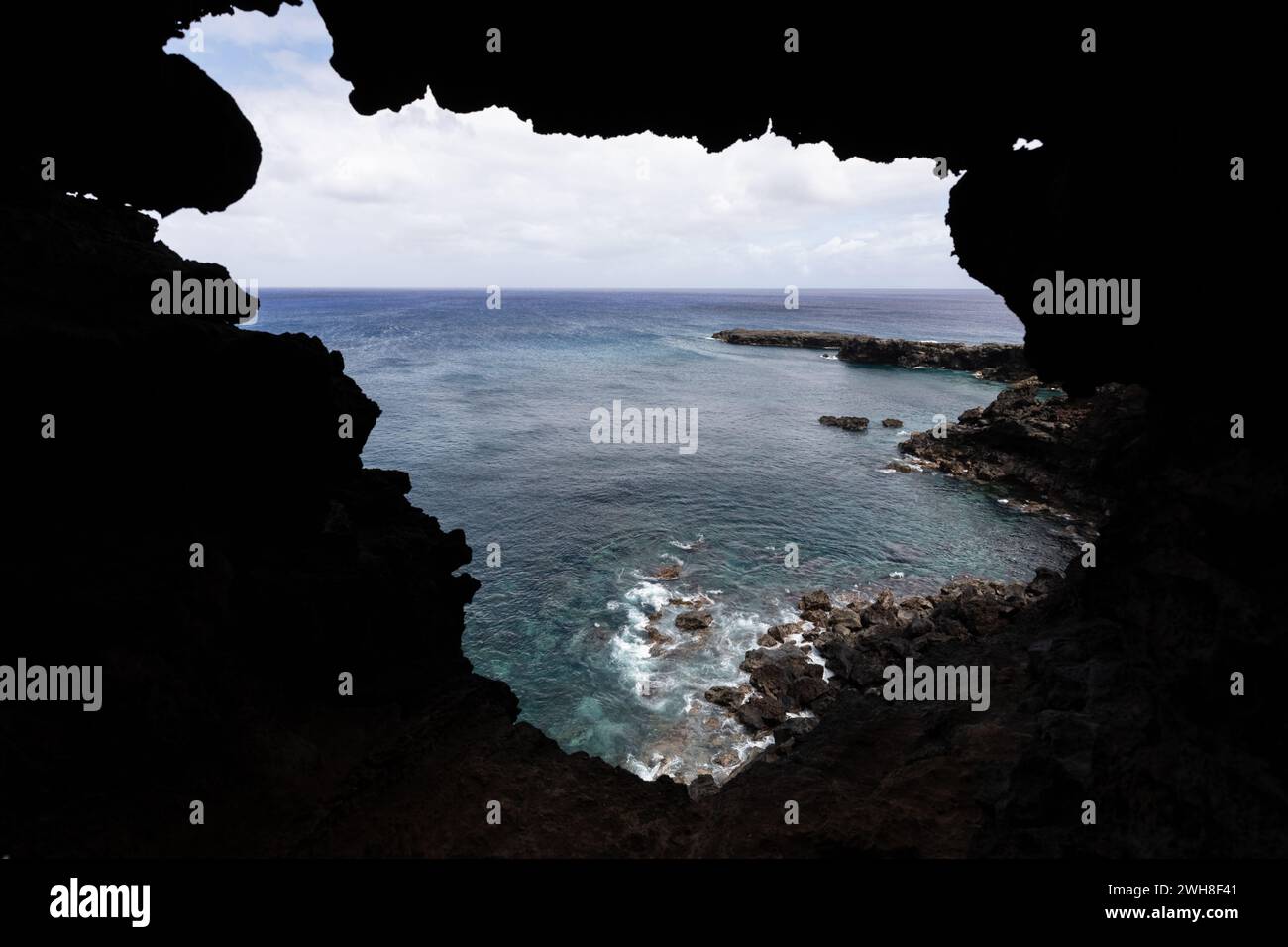The Ana Kakenga lava cave with an exit hole over the blue ocean of the ...