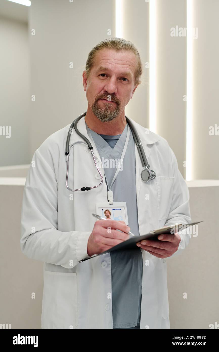 Confident experienced doctor with stethoscope looking at camera while ...