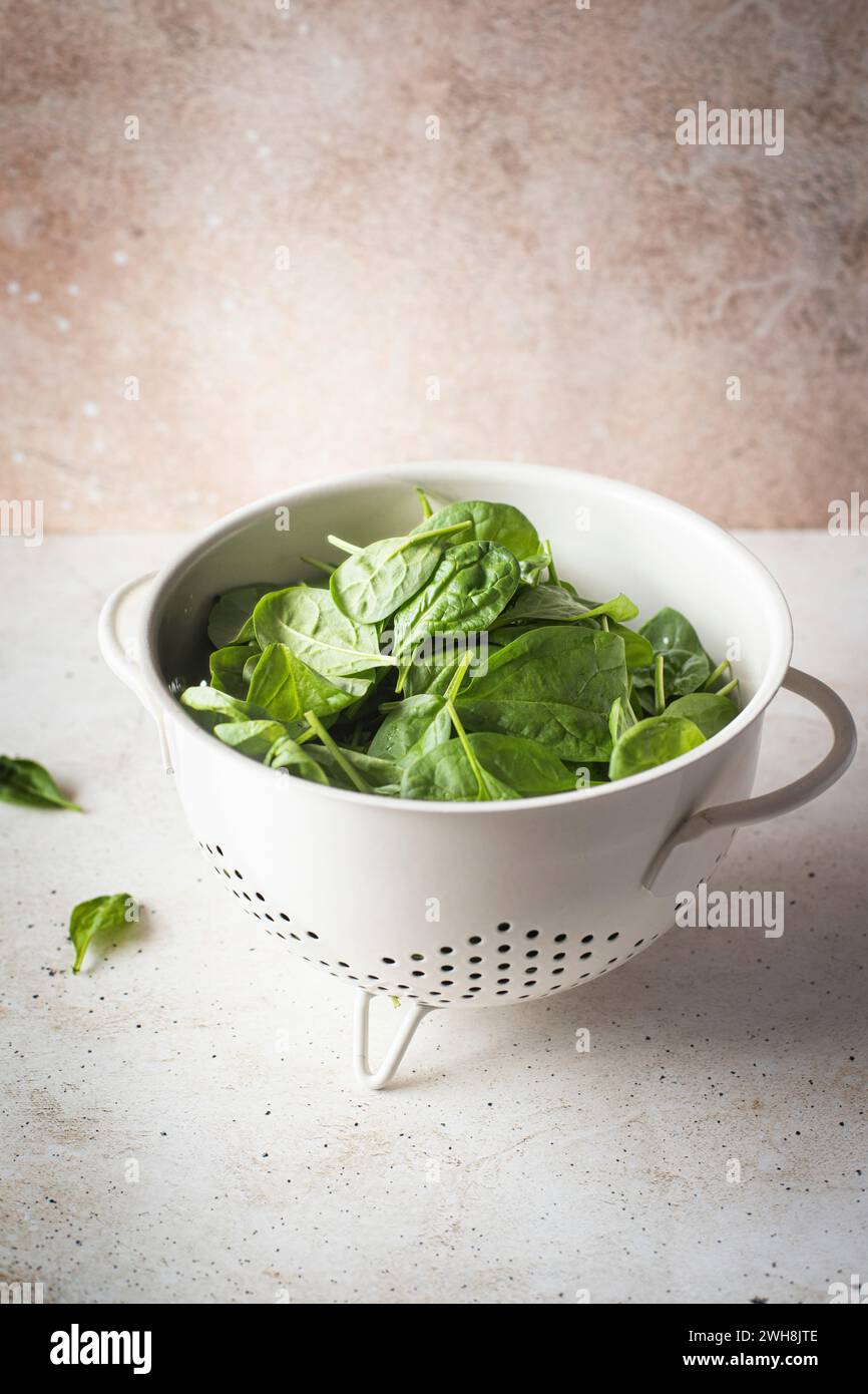 Sinach drying in a cullender against a white background Stock Photo - Alamy