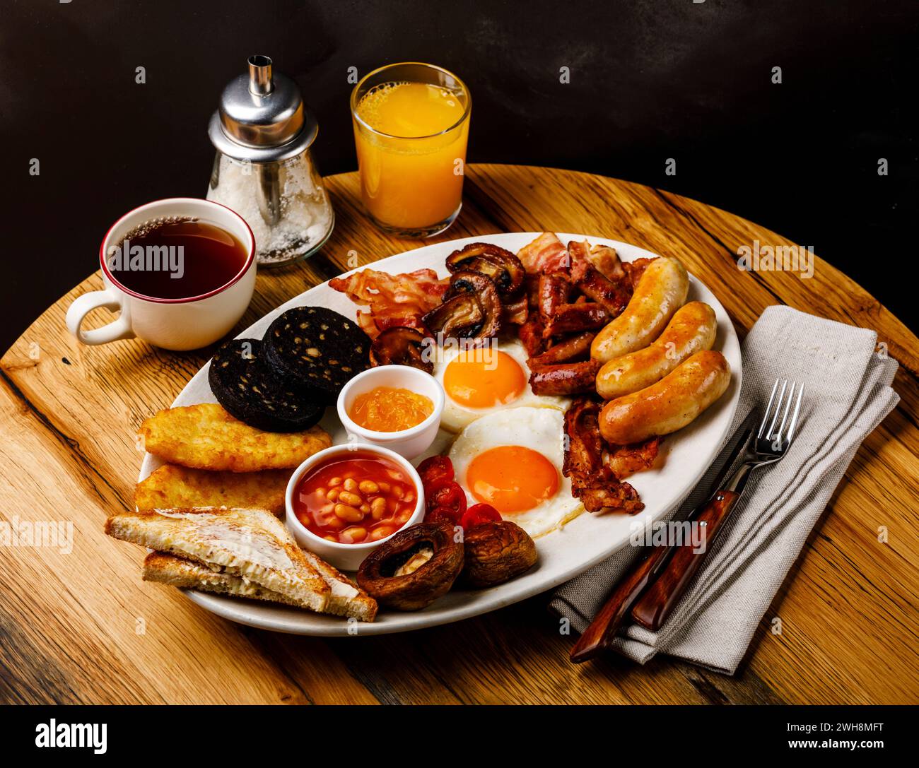 Full fry up English breakfast with fried eggs, sausages, bacon, black ...