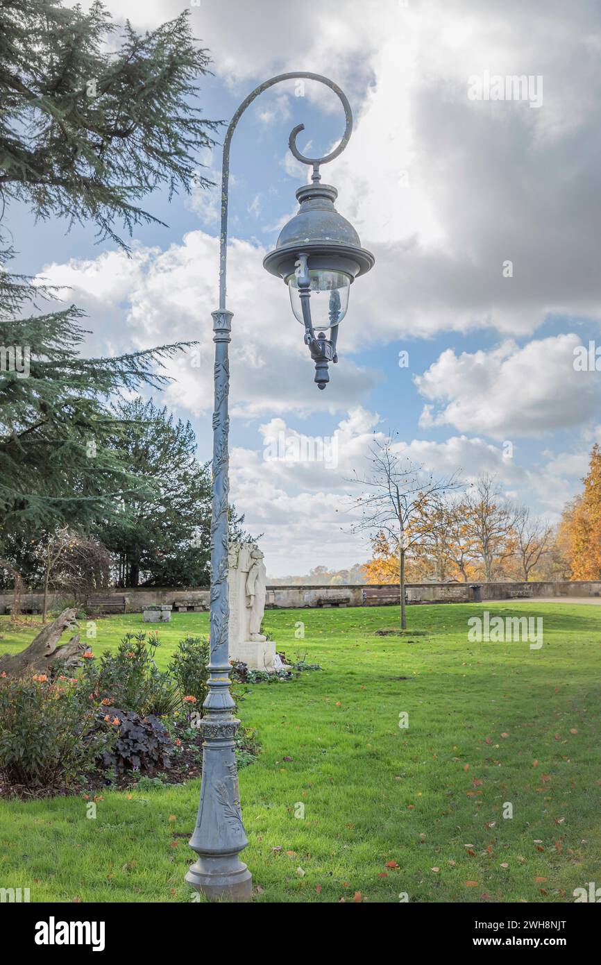 Ancient ornate light on the grass next to a pathway in a castle garden ...
