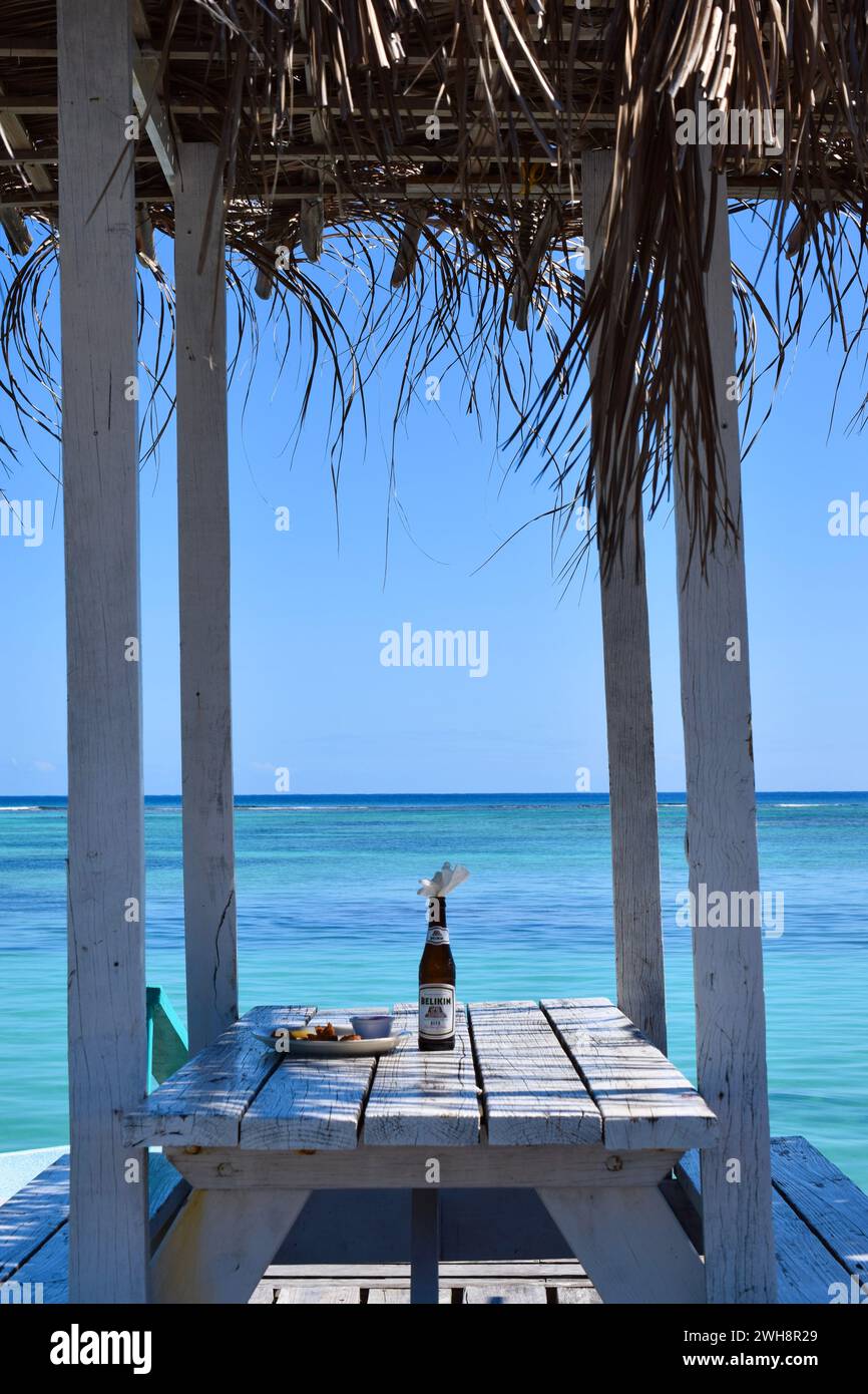 A shaded table, over turquoise water, with food and the national beer ...