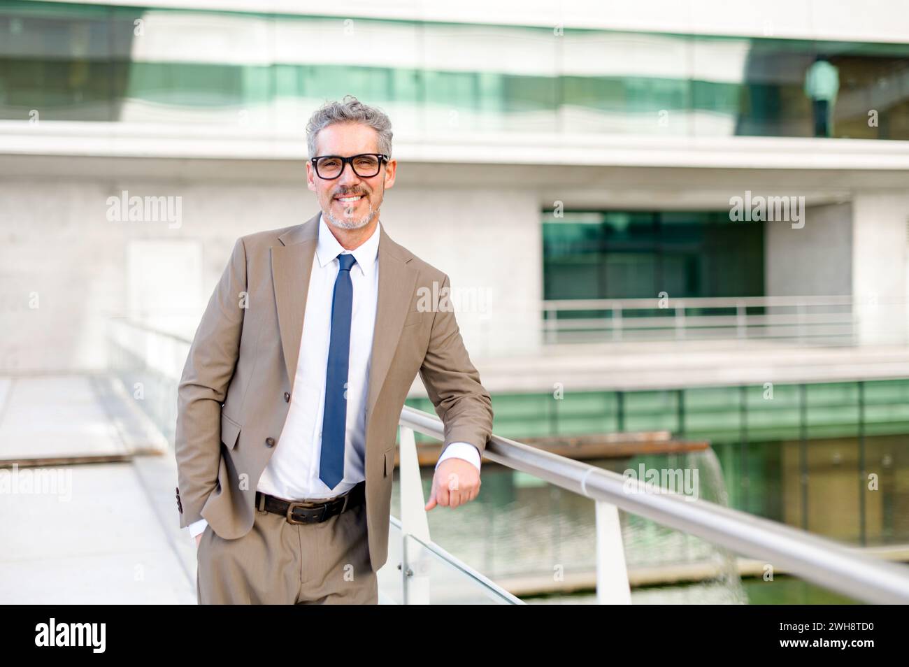 The seasoned businessman leans casually against a railing, his posture ...