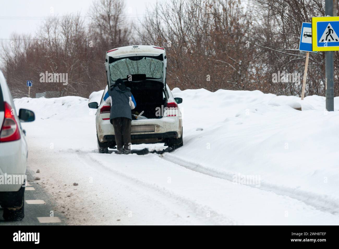Consequences of snowfall The driver opened the trunk of a car parked on ...
