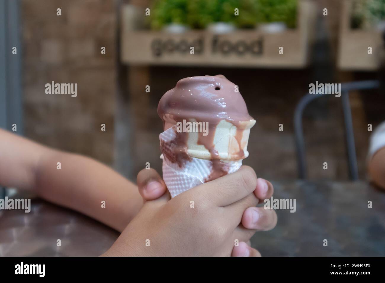 A young child's hand holding a dripping chocolate ice cream cone in the ...