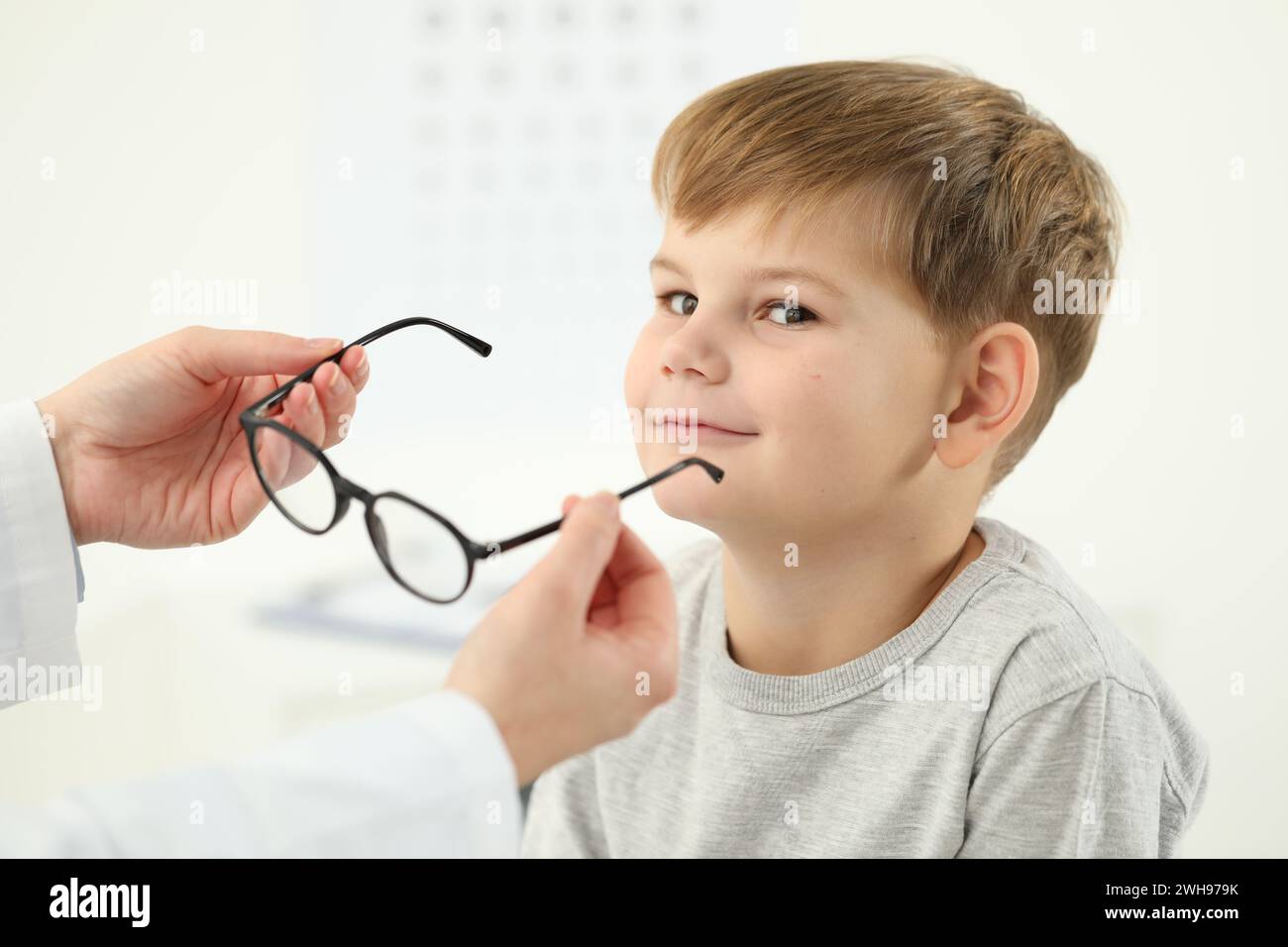 Vision testing. Ophthalmologist giving glasses to little boy indoors ...